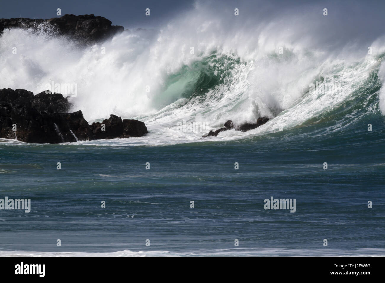 Ocean wave crashing against the rocks at Waimea bay on the north shore ...