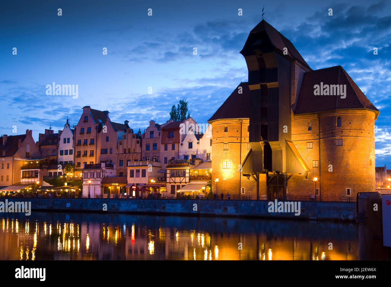 Poland, Gdansk. Buildings reflect in port water at sunset. Credit as ...