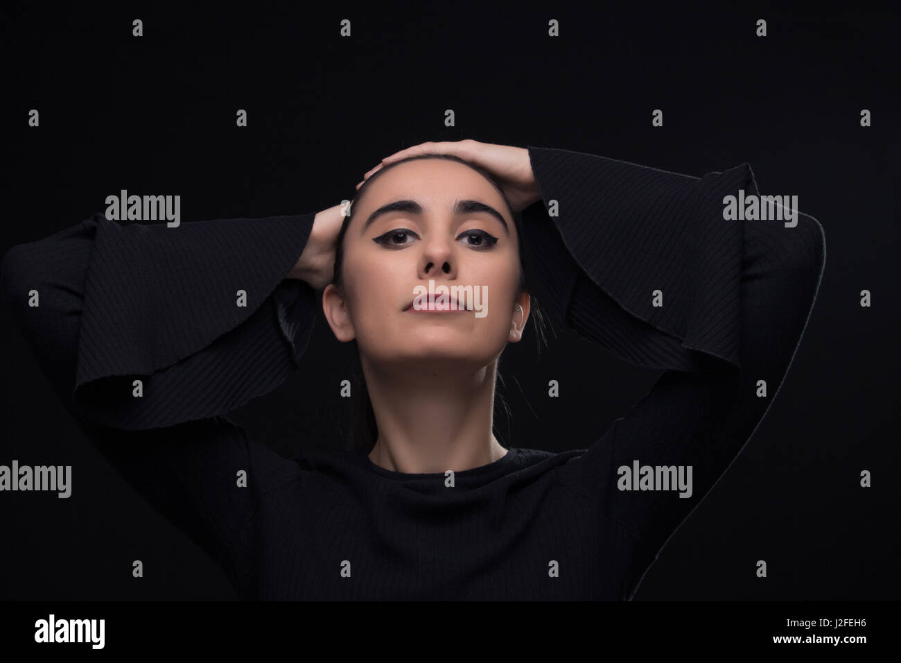 one young adult woman, black clothes head face, black background studio ...