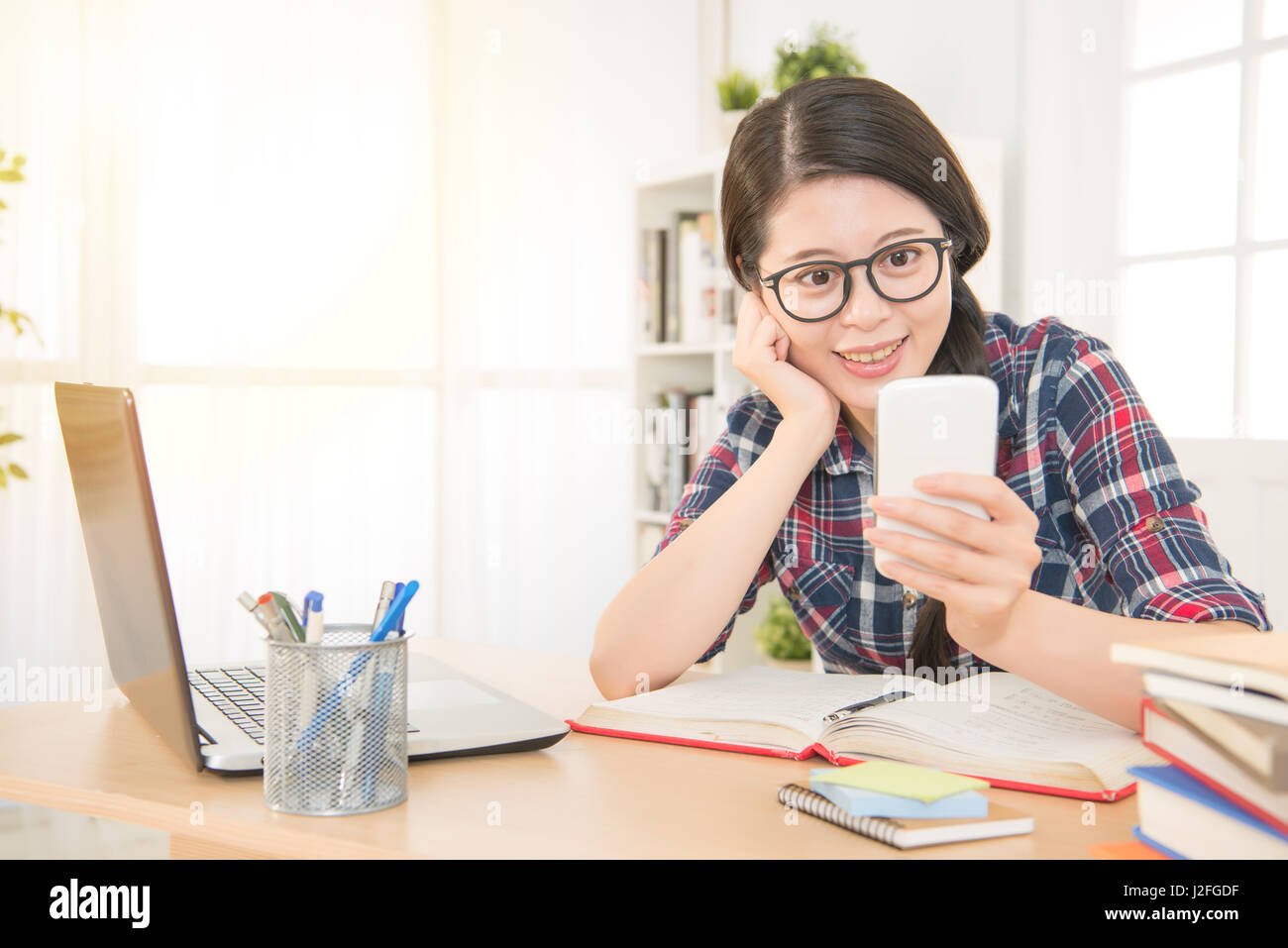 Beautiful relaxed student learning with laptop and texting in a mobile ...