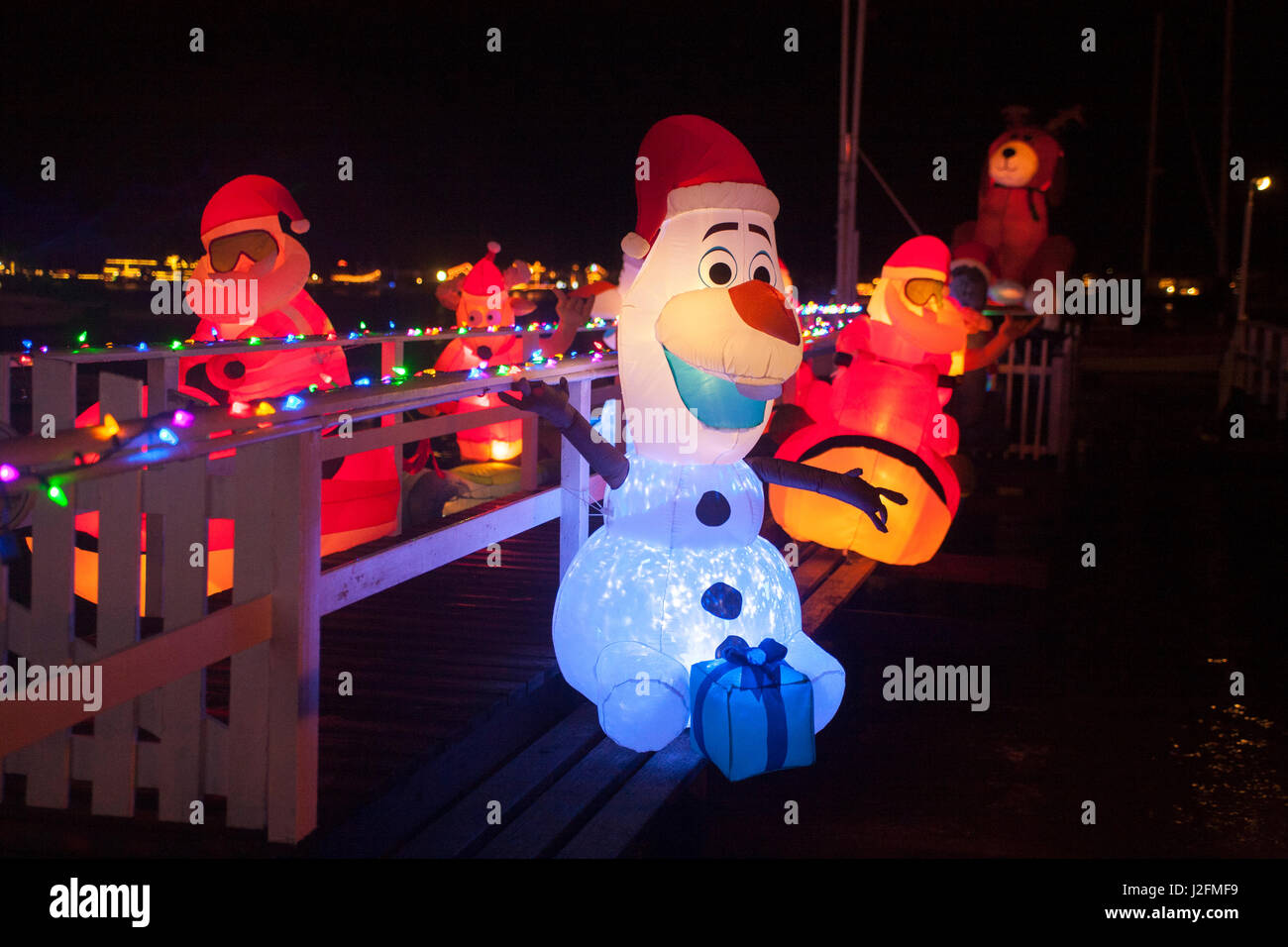 Jolly illuminated inflated Christmas cartoon characters decorate a dock ...