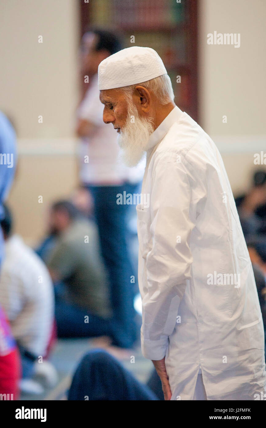 An elderly Middle Eastern American man in tradition dress prays during ...