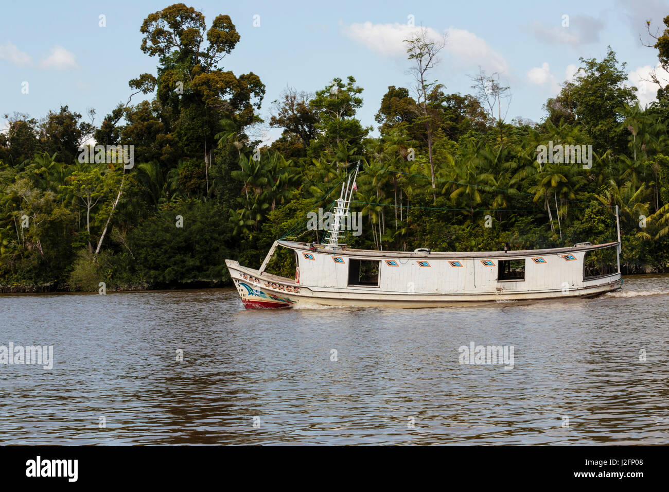 South America, Brazil, Amazon River. Traditional painted boat traveling ...