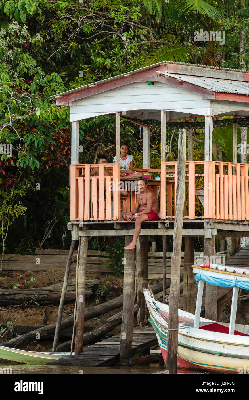 South America, Brazil, Amazon River. Family sitting on structure above ...