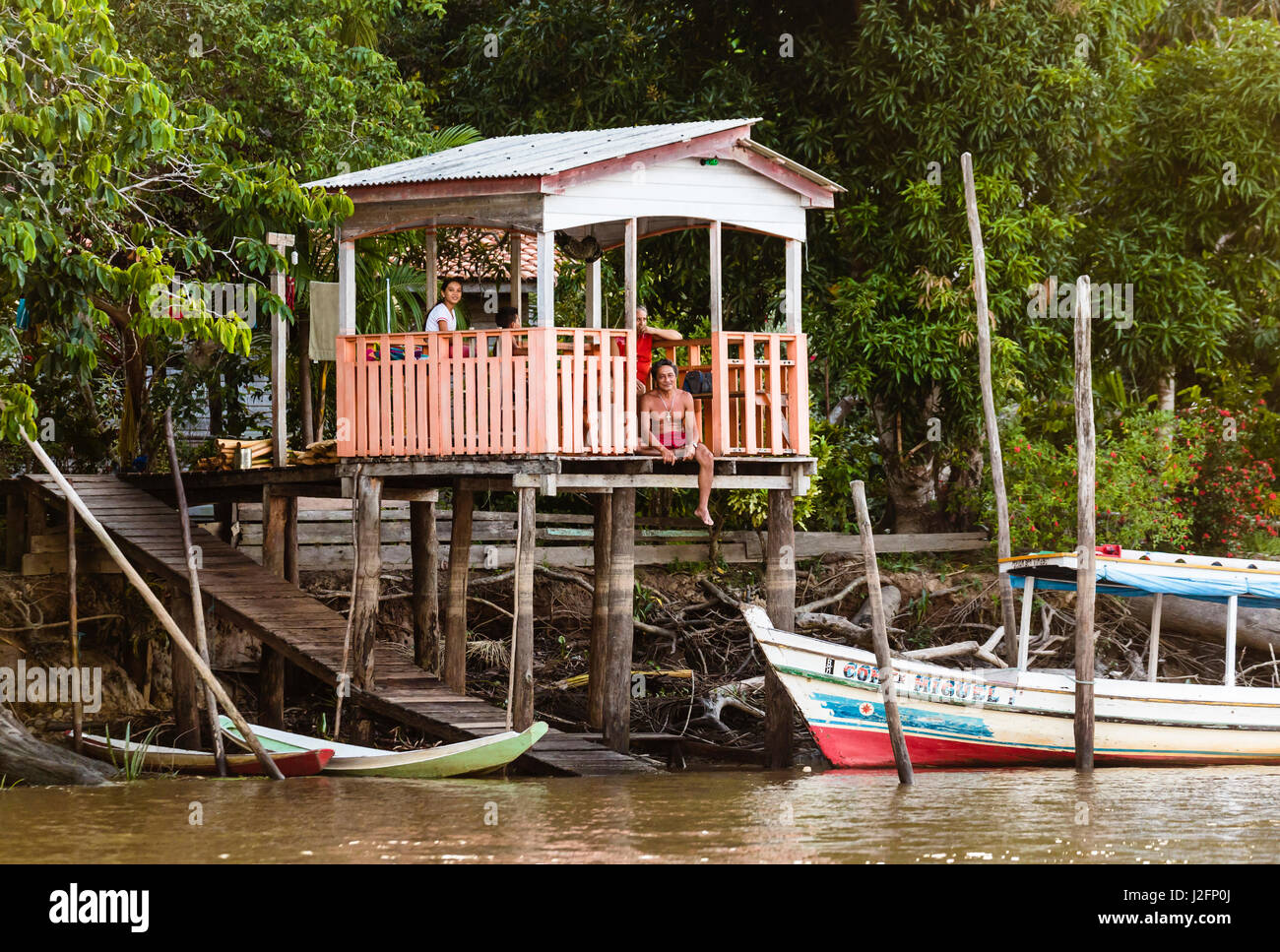 South America, Brazil, Amazon River. Family sitting on structure above ...