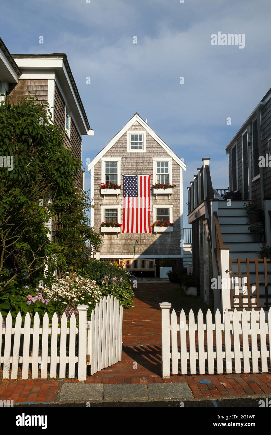 A gate opens towards a pretty house with flower boxes on the windows ...