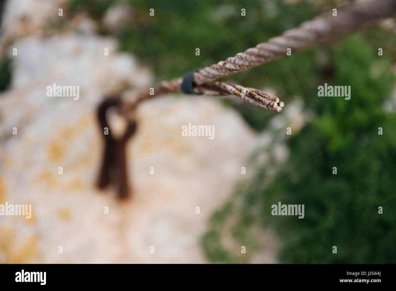 Rusty metal cable tied to a metal loop in the ground closeup blurred ...
