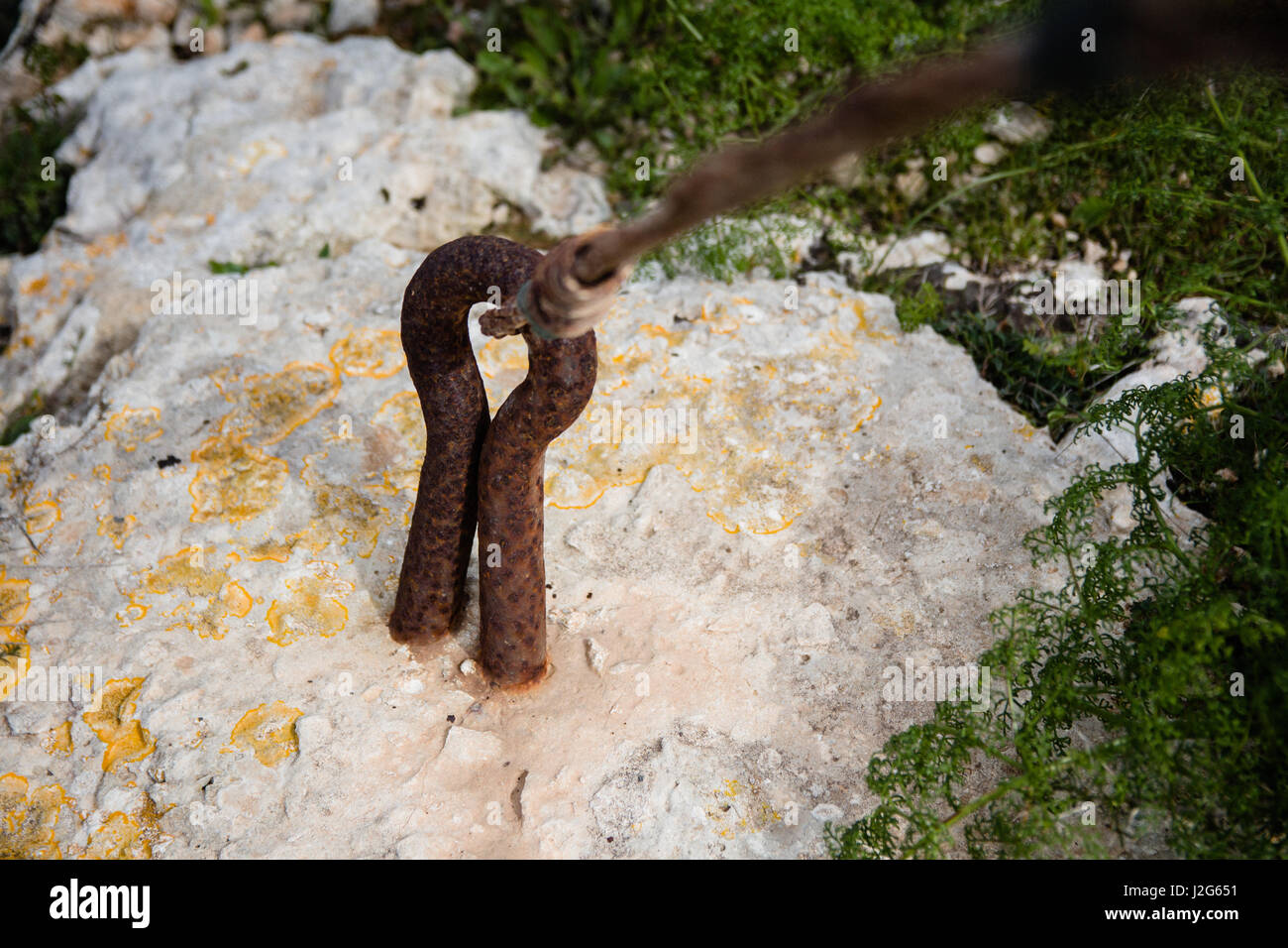 Rusty metal cable tied to a metal loop in the ground closeup blurred ...