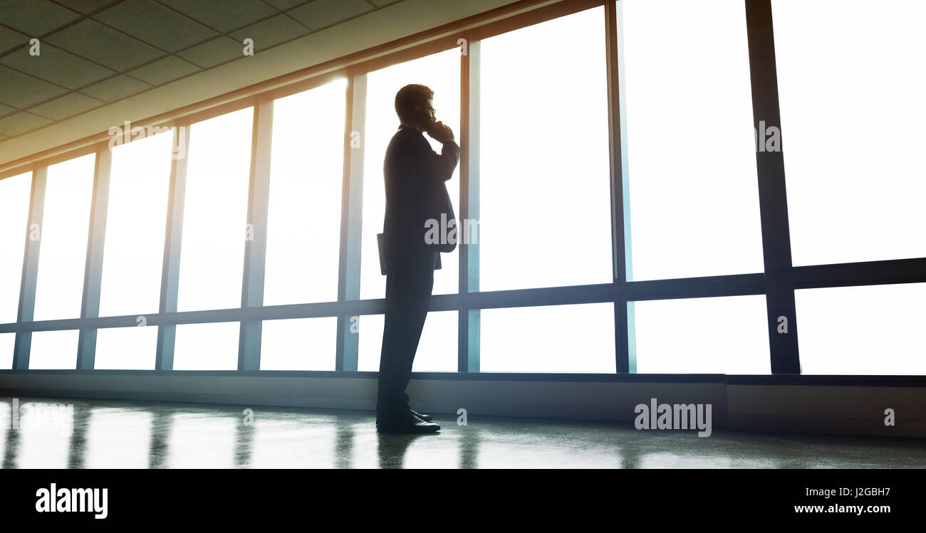 Full length shot of businessman standing near office window and talking ...