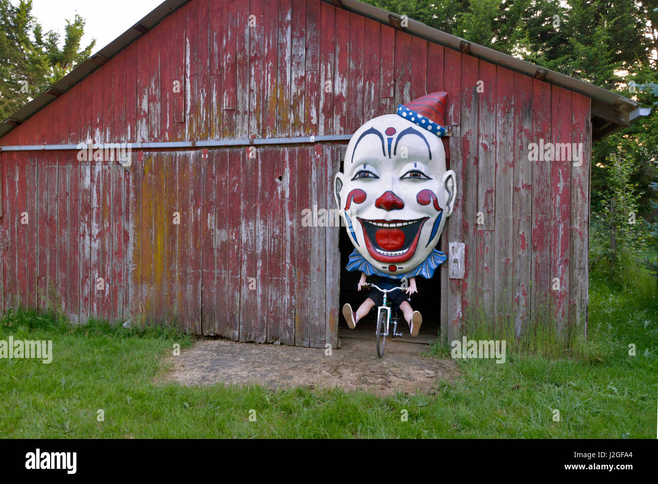 USA, Oregon, Oregon City. Clown face on bike in door of red barn ...
