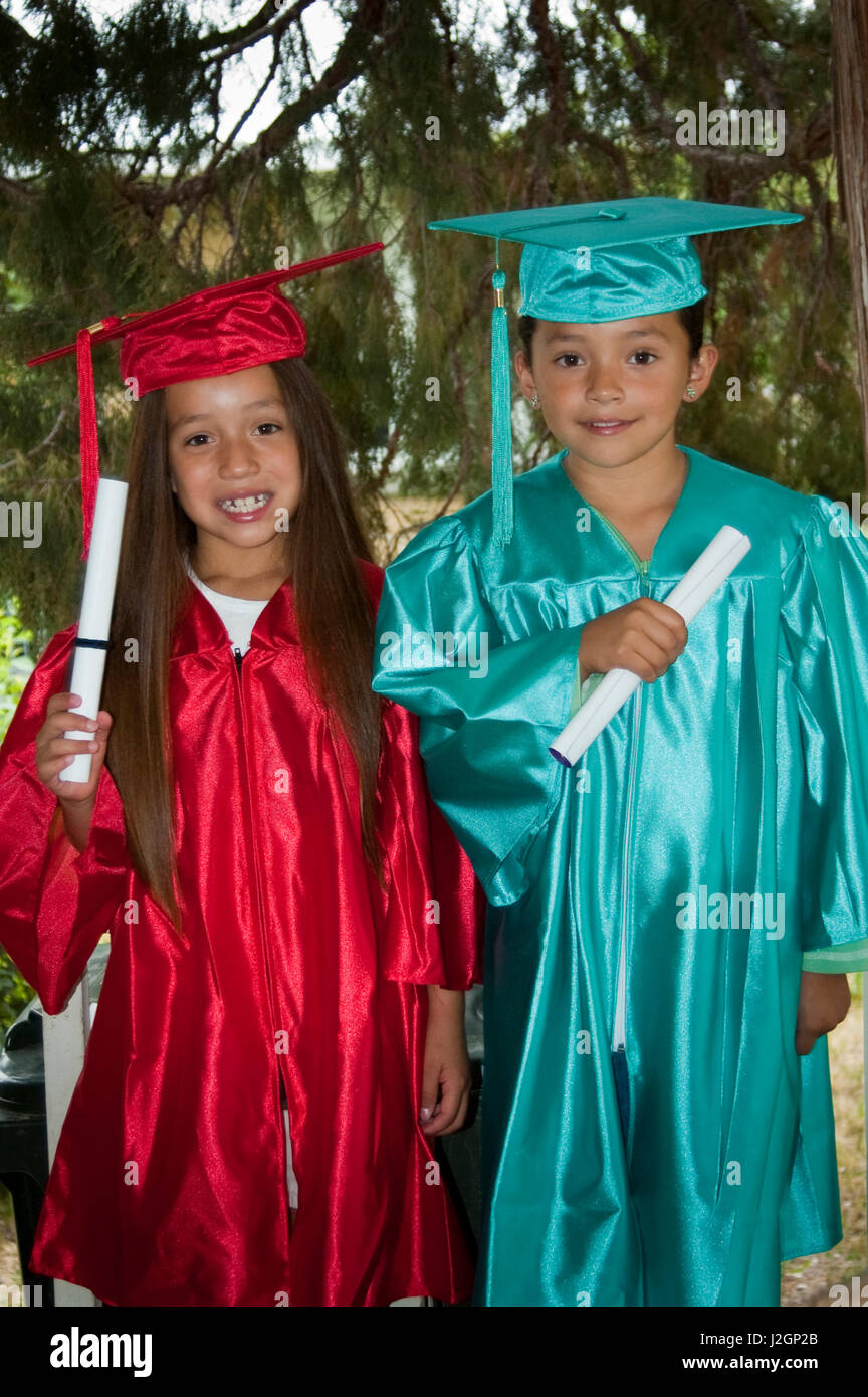 Two Native American sisters, dressed in graduation cap and gowns, hold ...