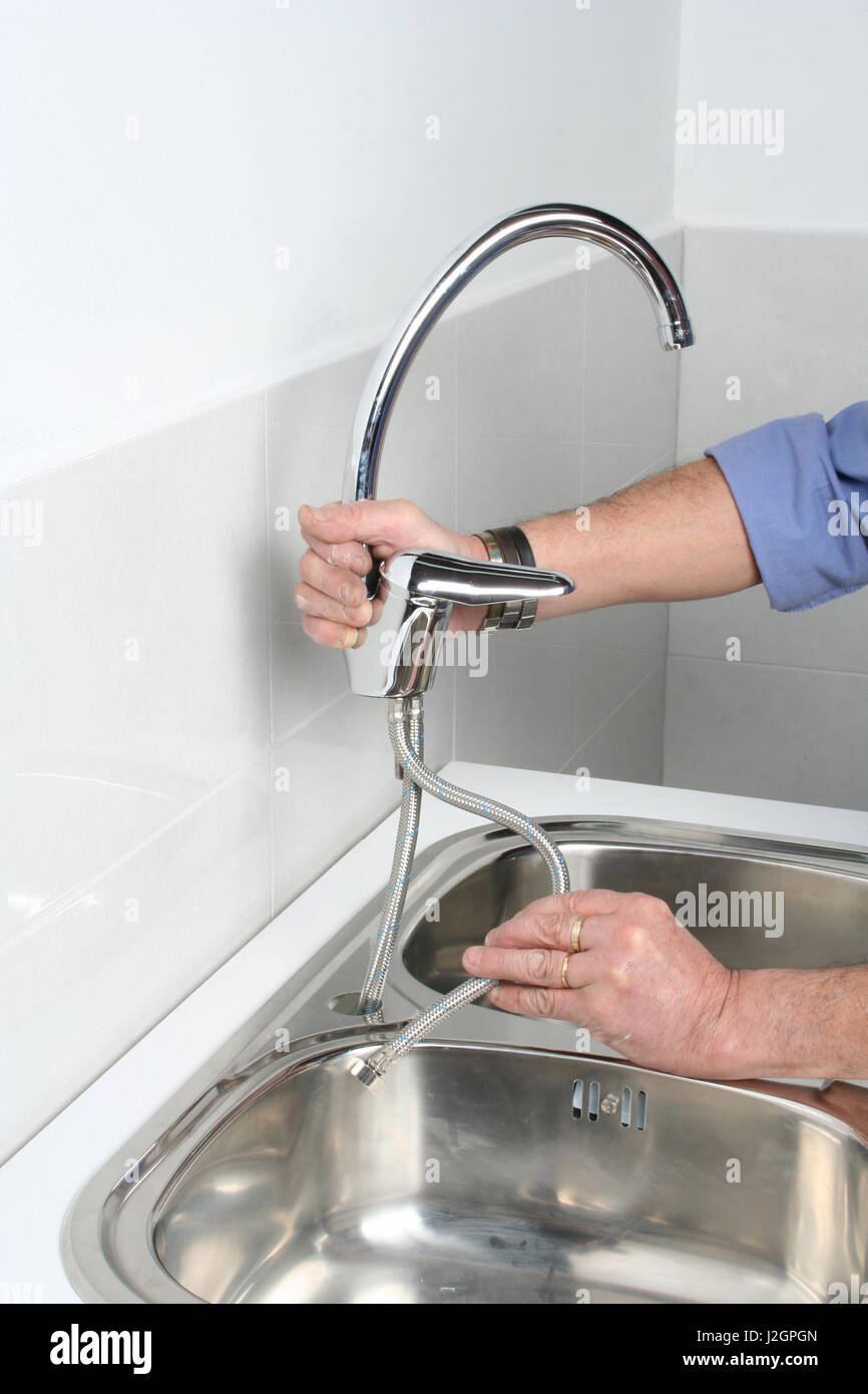 Plumber installing a faucet in a stainless steel kitchen sink Stock ...