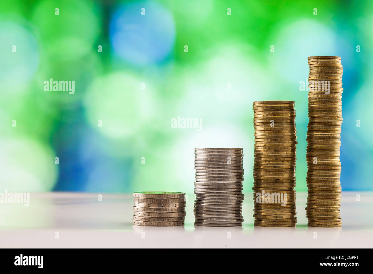 Growing coins stacks with green and blue sparkling bokeh background. Financial growth, saving ...