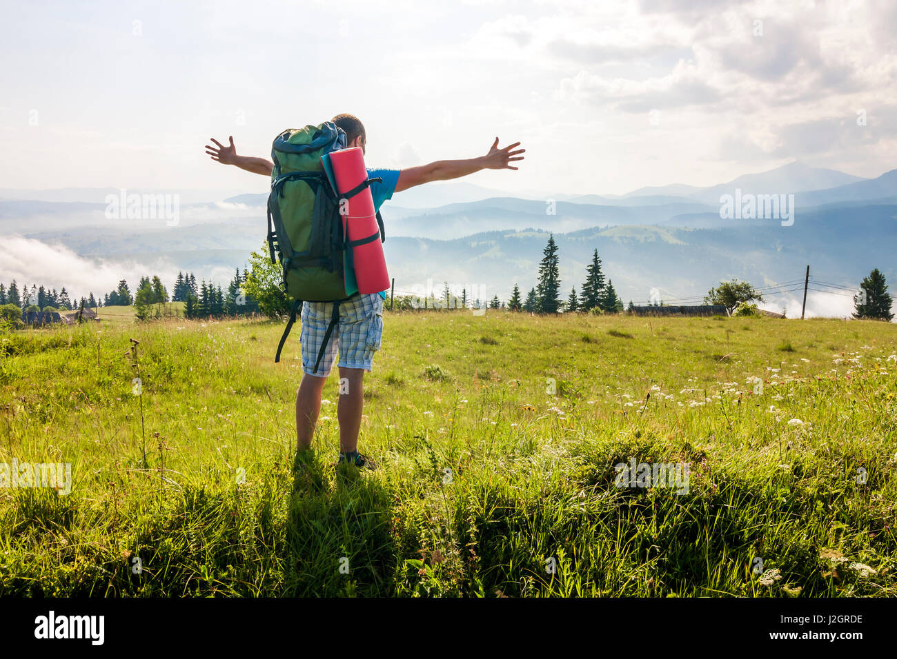 Hiker with a backpack standing in mountains Stock Photo - Alamy