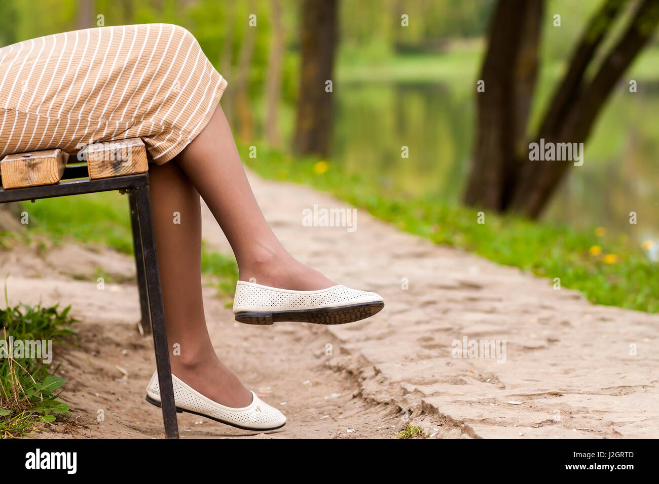 Feet of beautiful young woman sitting on bench in park Stock Photo - Alamy