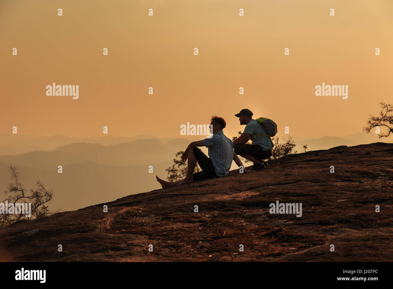 Group of tourists watching the sunset on top of the mountain. Rest ...