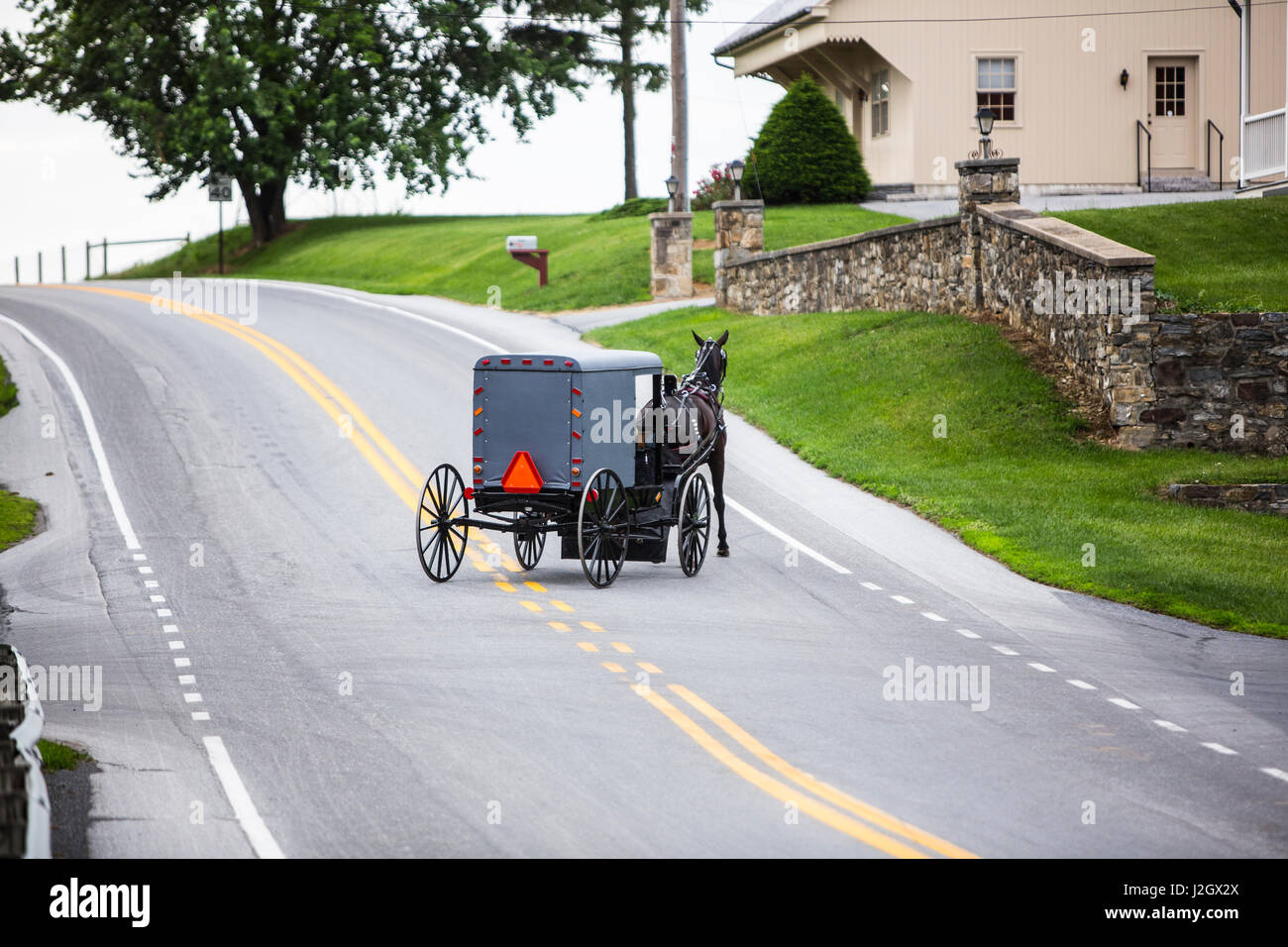 Lancaster, Pennsylvania. Amish grey buggy and horse turn uphill on a ...