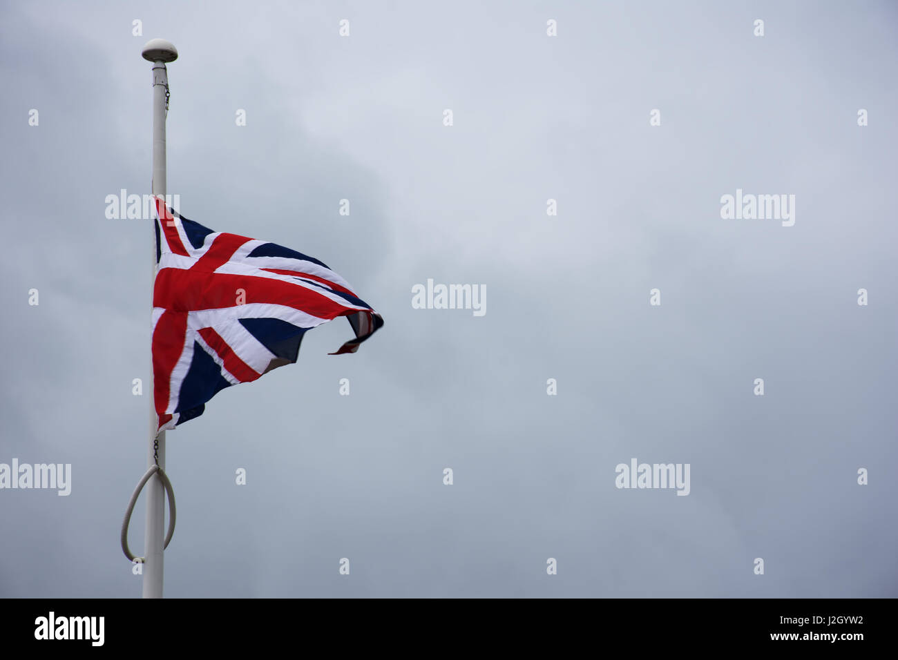 British flag,Union Jack waving on wind against grey,cloudy sky.Uk flag ...