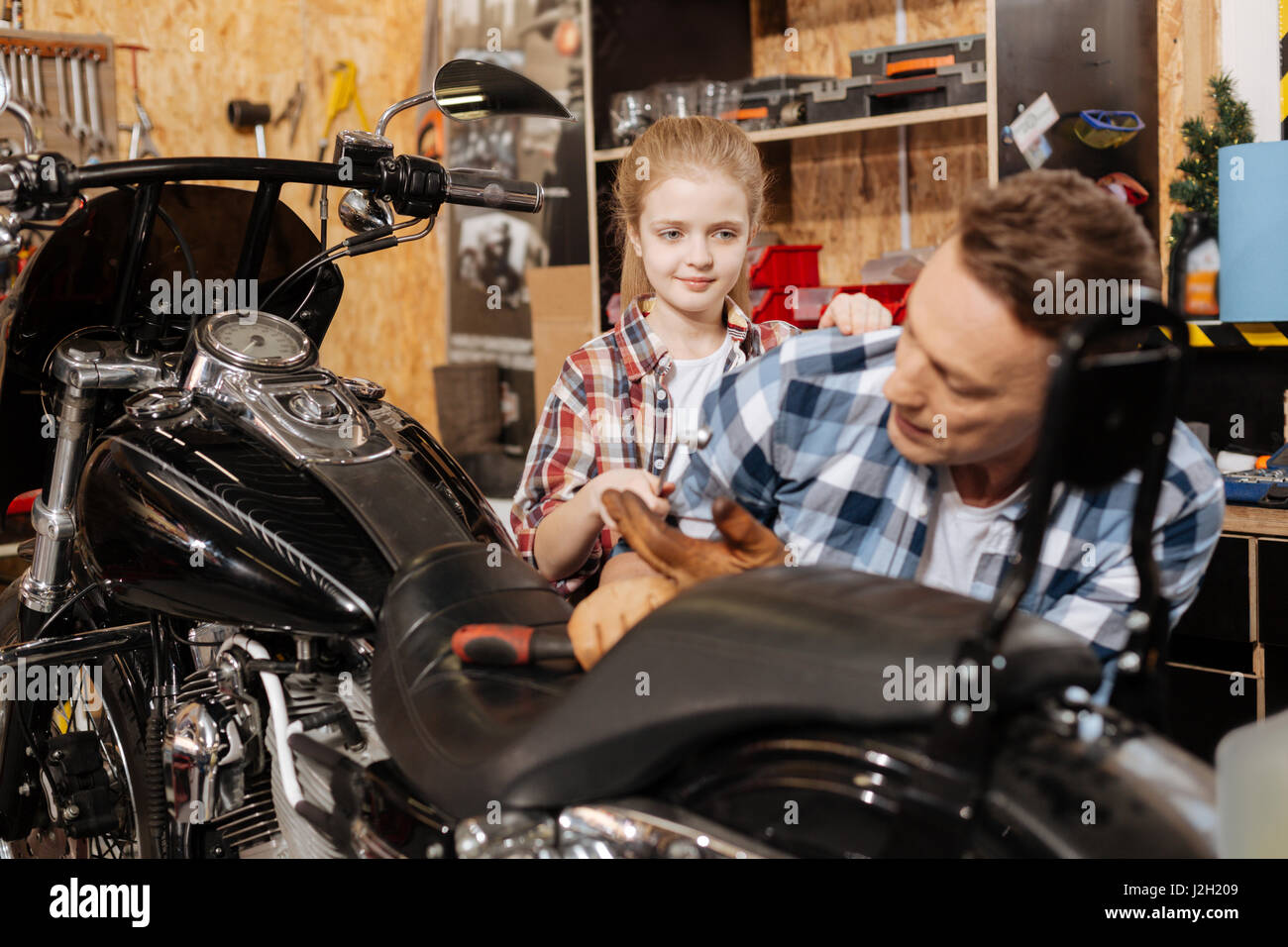 Supporting active girl handing her dad a wrench Stock Photo - Alamy