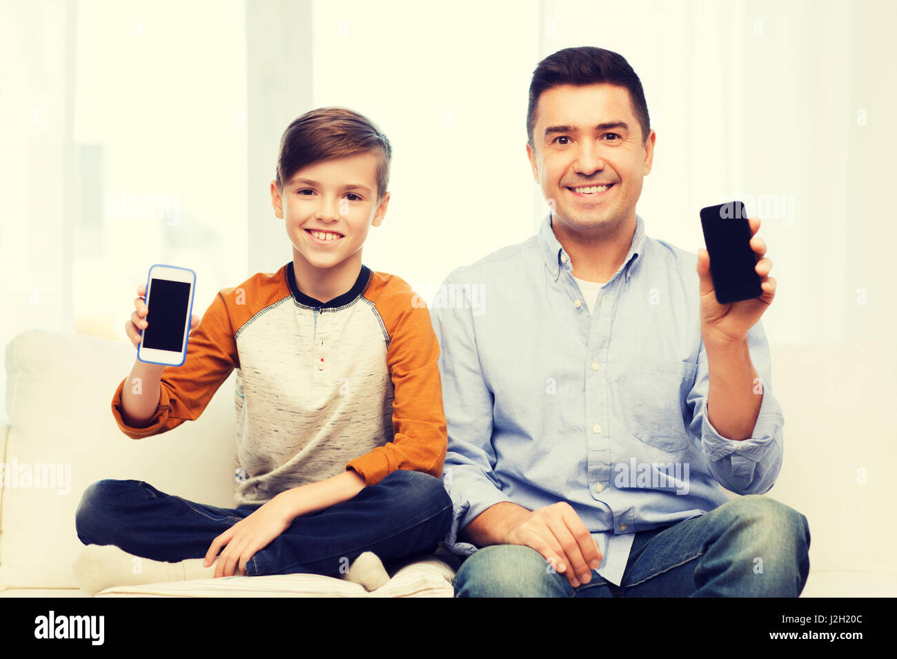 happy father and son with smartphones at home Stock Photo - Alamy