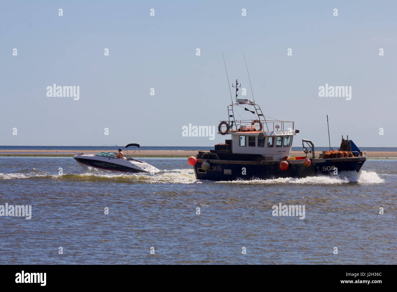 Powerboat and fishing boat passing each other Stock Photo - Alamy