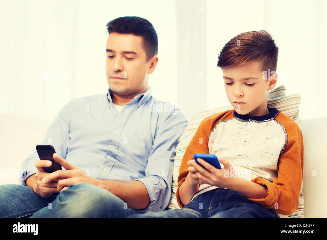 father and son with smartphones at home Stock Photo - Alamy