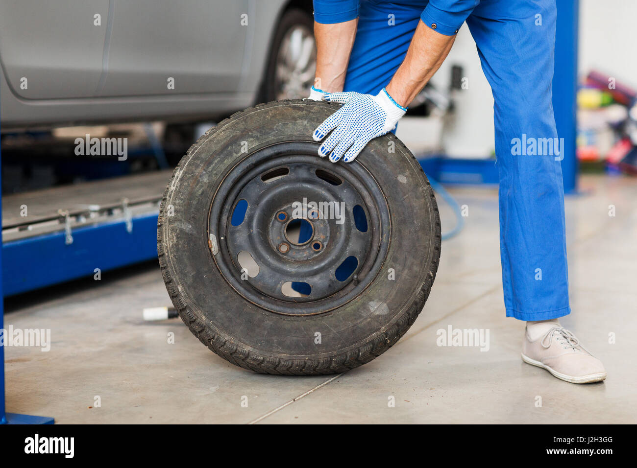 mechanic with wheel tire at car workshop Stock Photo - Alamy