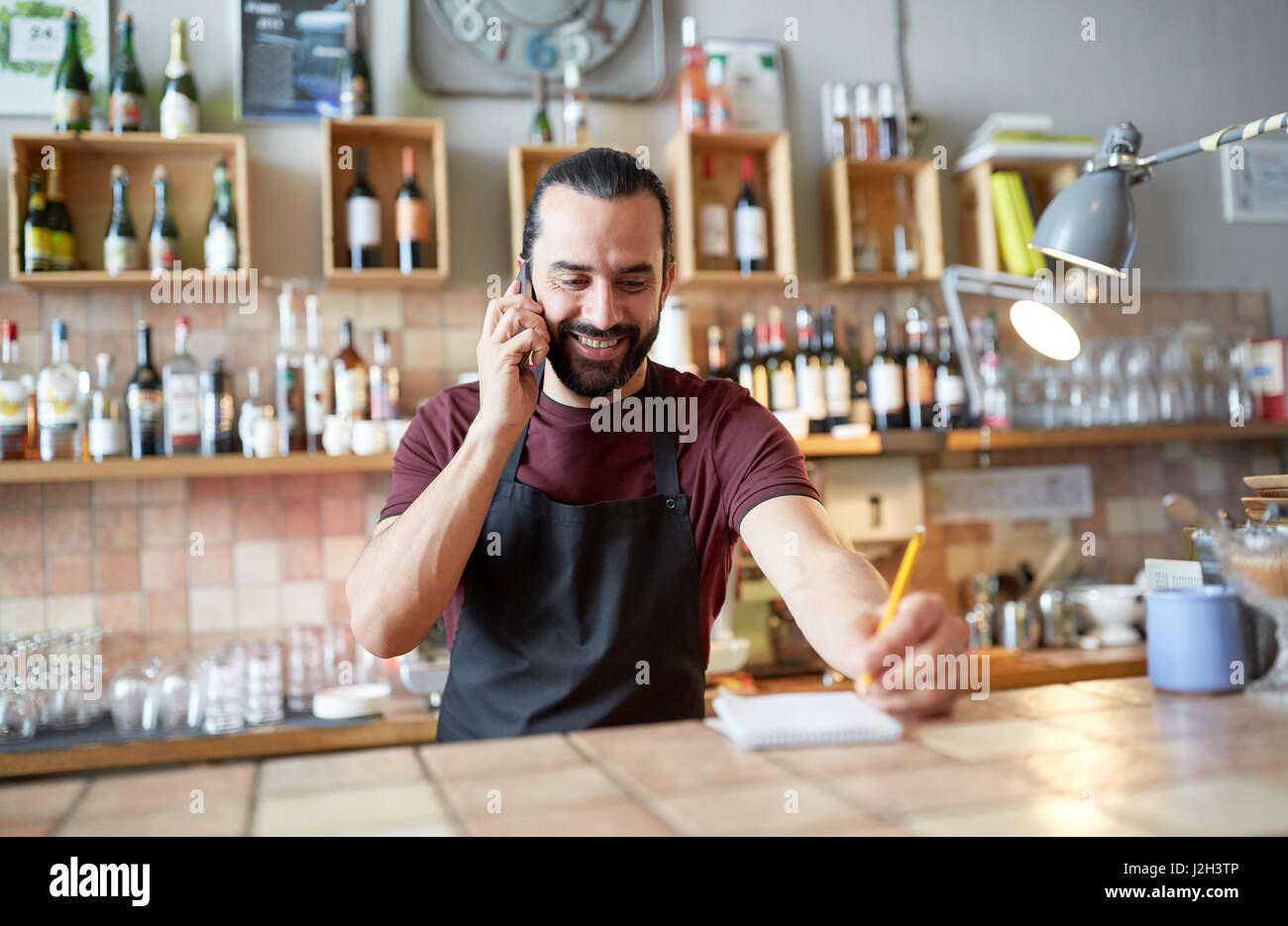 happy man or waiter at bar calling on smartphone Stock Photo - Alamy