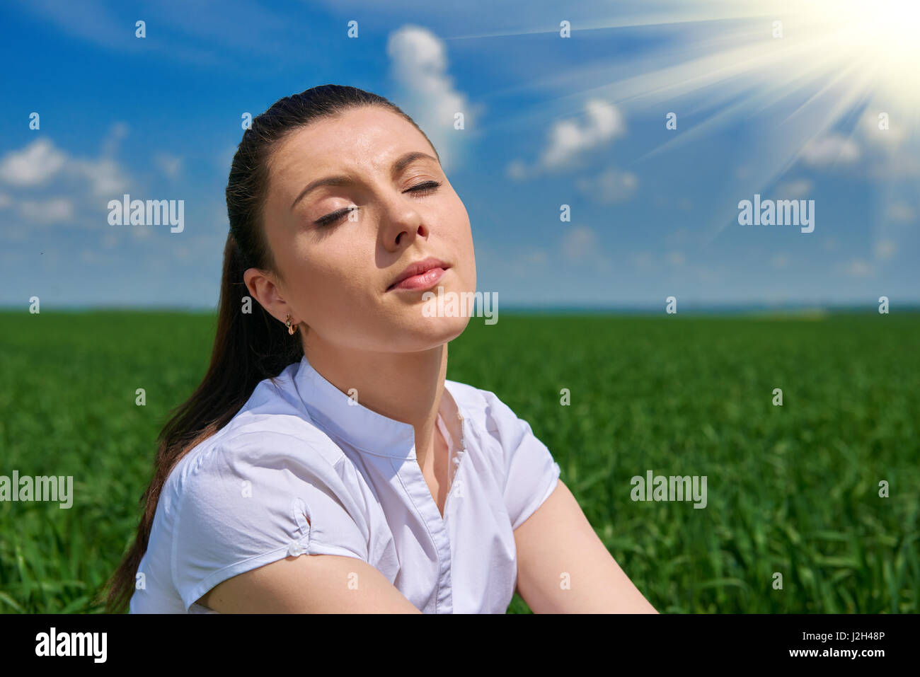 Business woman relaxing in green grass field outdoor under sun ...