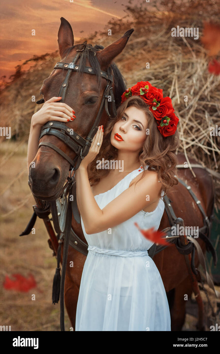 Girl hugging a horse's head. She is very beautiful in a white dress ...