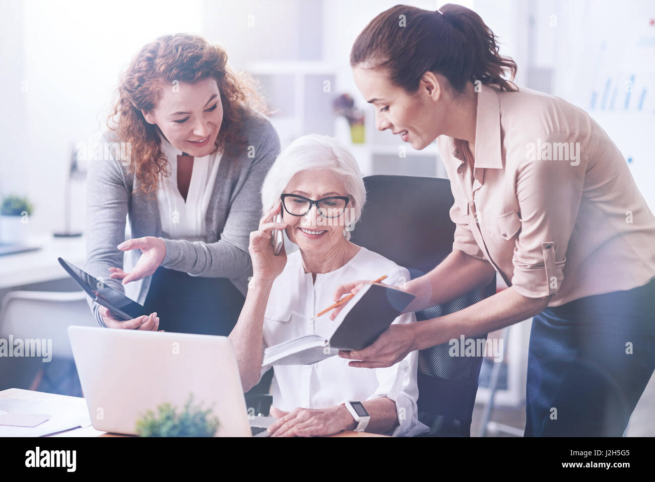 Two female office workers helping their boss Stock Photo - Alamy