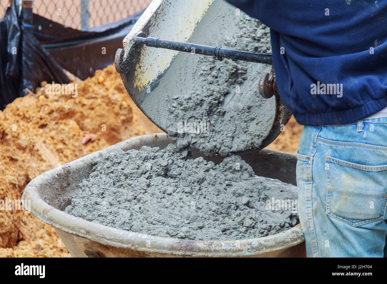 Concrete being poured from a truck into a concrete pump at a ...