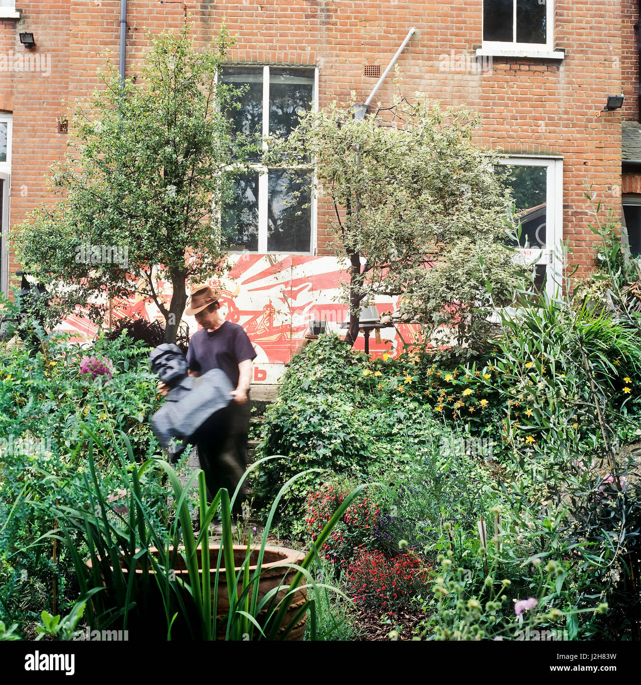 Man carrying sculpture in the back garden of house Stock Photo - Alamy