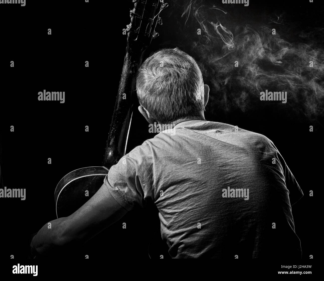 The musician has a rest, embracing his guitar, smoking Stock Photo - Alamy
