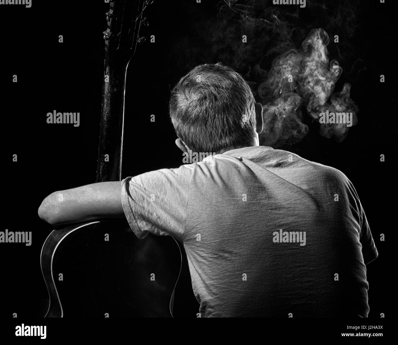 The musician has a rest, embracing his guitar, smoking Stock Photo - Alamy