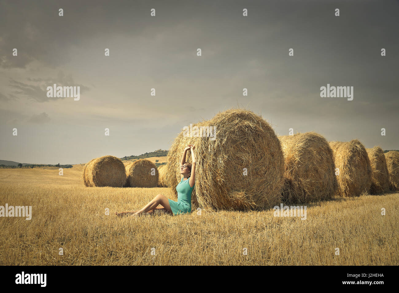 Woman leaning on haystack Stock Photo - Alamy