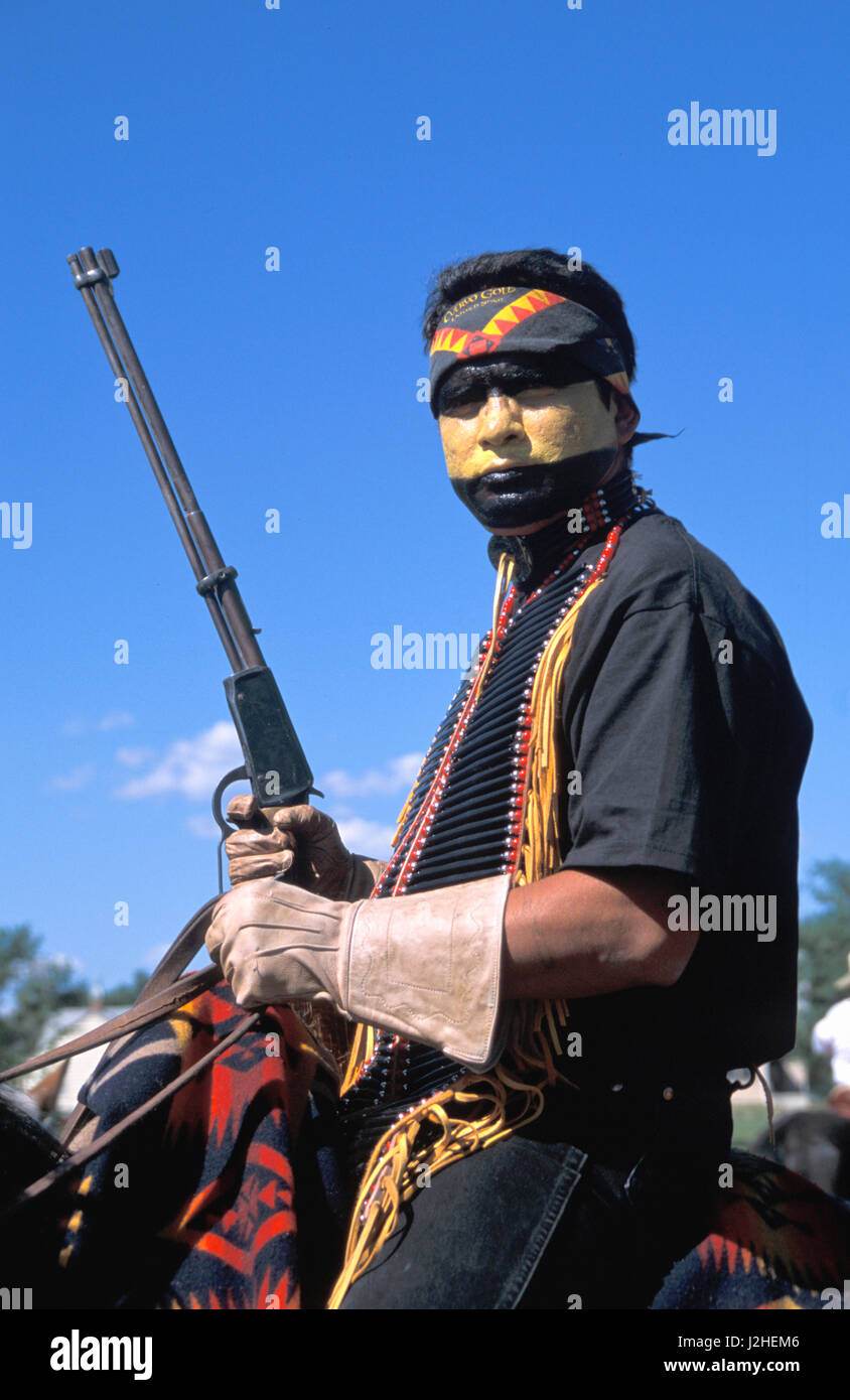 Blackfeet man with painted face holds a rifle on horseback during the ...