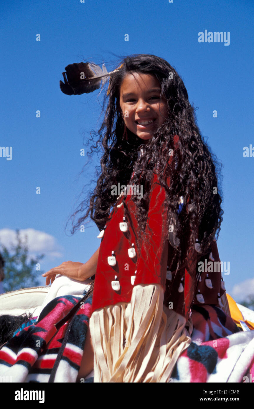 Smiling Blackfeet girl on horseback, Lynn Mad Plume, wearing a deep red ...