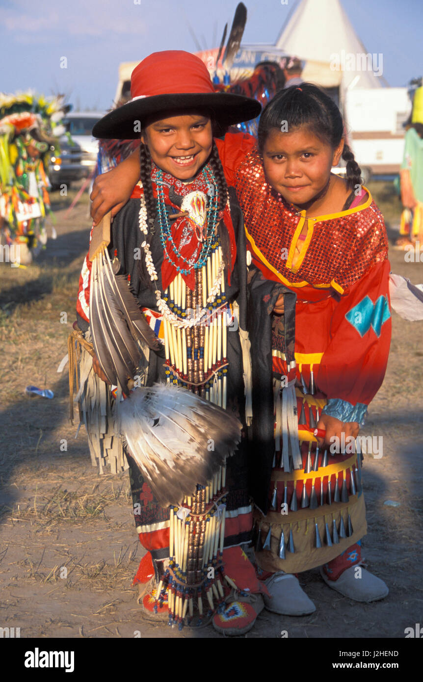 Two young pow wow buddies dressed in traditional regalia are arm in arm ...