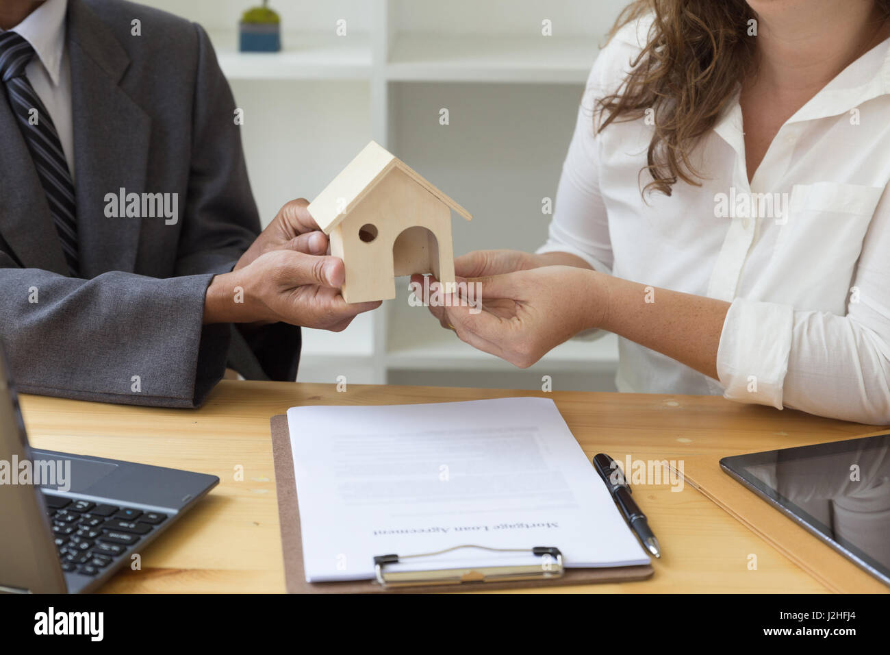 Hands giving house model to other hands with agreement on desk. house ...