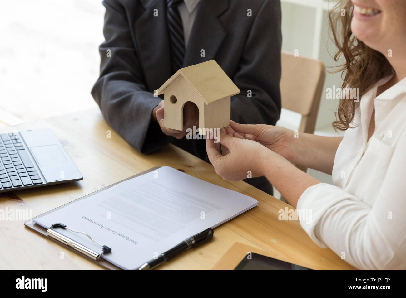 Hands giving house model to other hands with agreement on desk. house ...