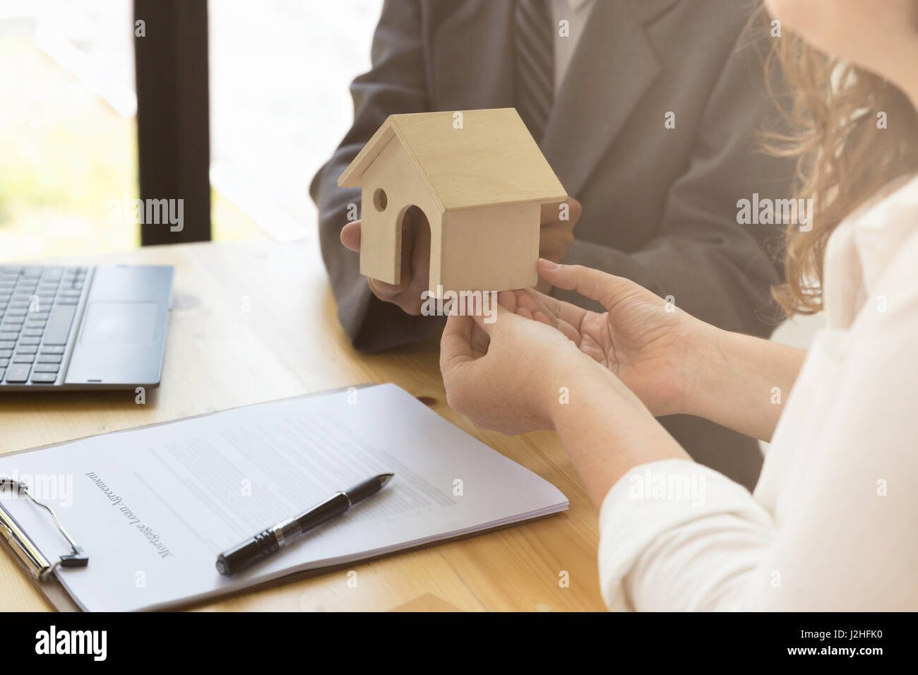 Hands giving house model to other hands with agreement on desk. house ...