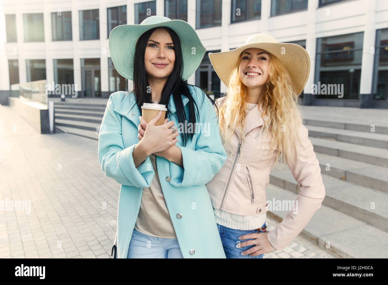 Happy long-haired girls in hats near building Stock Photo - Alamy