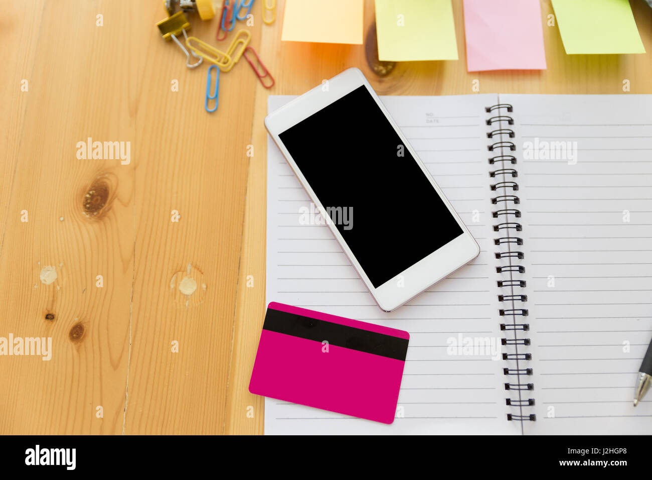 wood office table with smart phone, credit card, notebook, sticky note ...