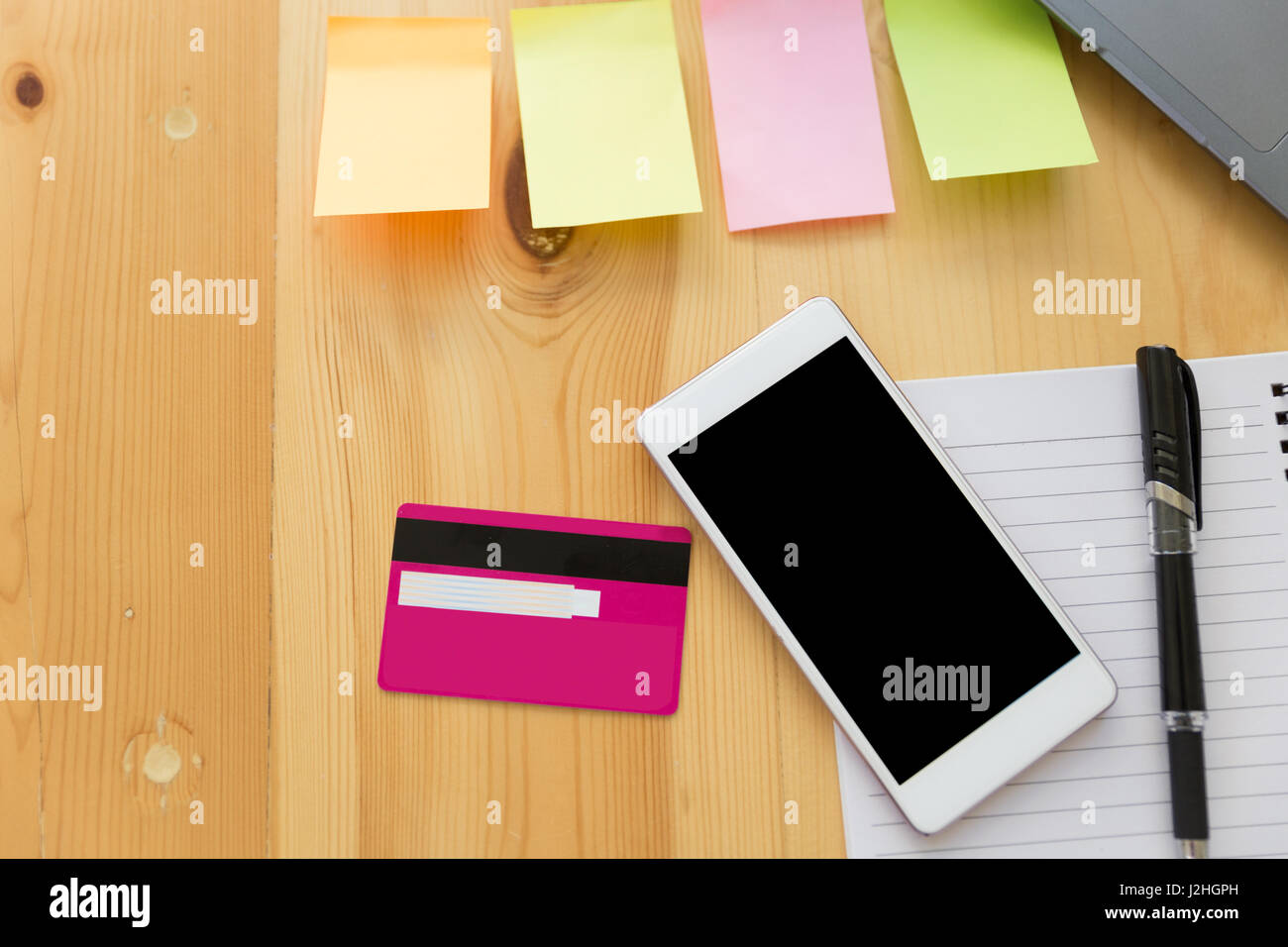 wood office table with smart phone, credit card, notebook, sticky note ...