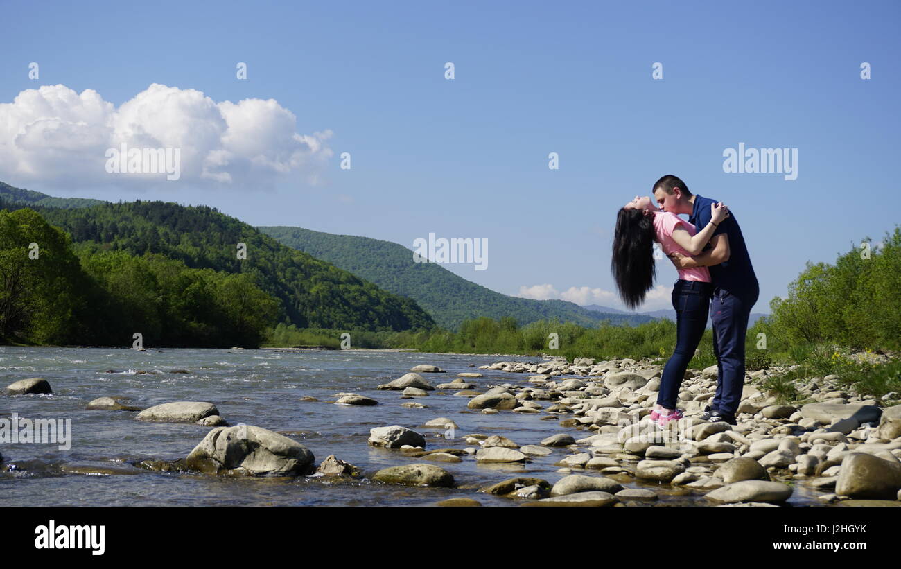 Happy young couple kissing with mountain river background Stock Photo ...