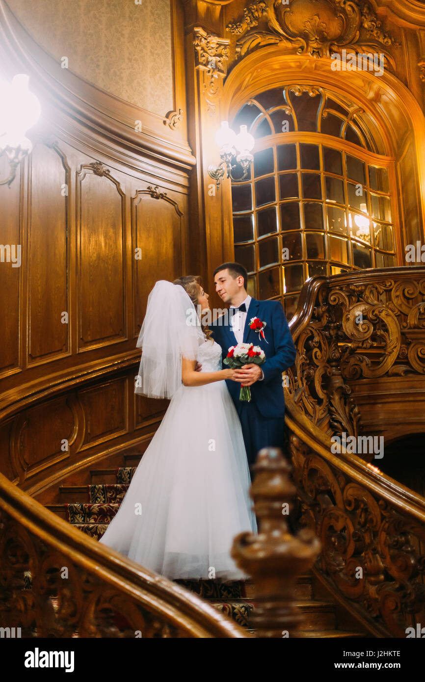 Charming bride and handsome elegant groom on old wooden stairs with the ...