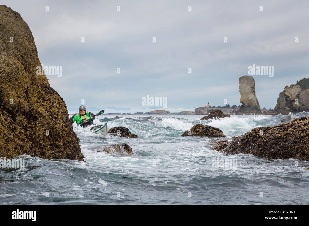 USA, Washington State, Woman sea kayaker in rock garden in moderate ...