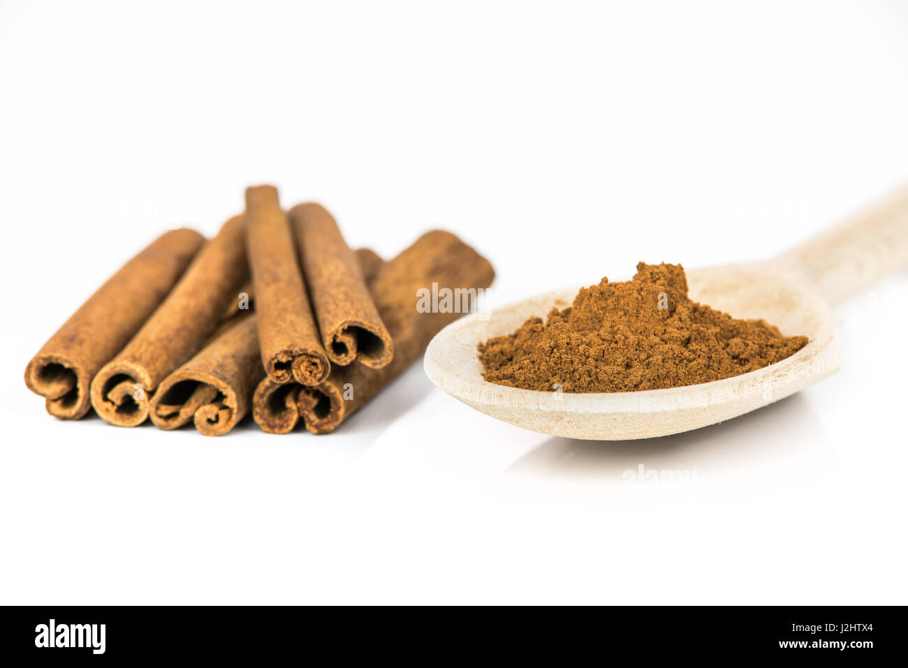 Cinnamon sticks and wooden spoon with ground cinnamon powder on white ...