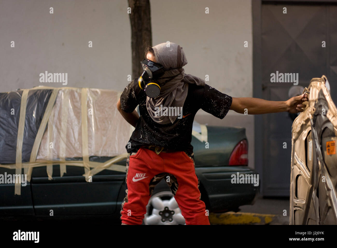 A protester in a street holding the hood of a car as a shield Stock ...